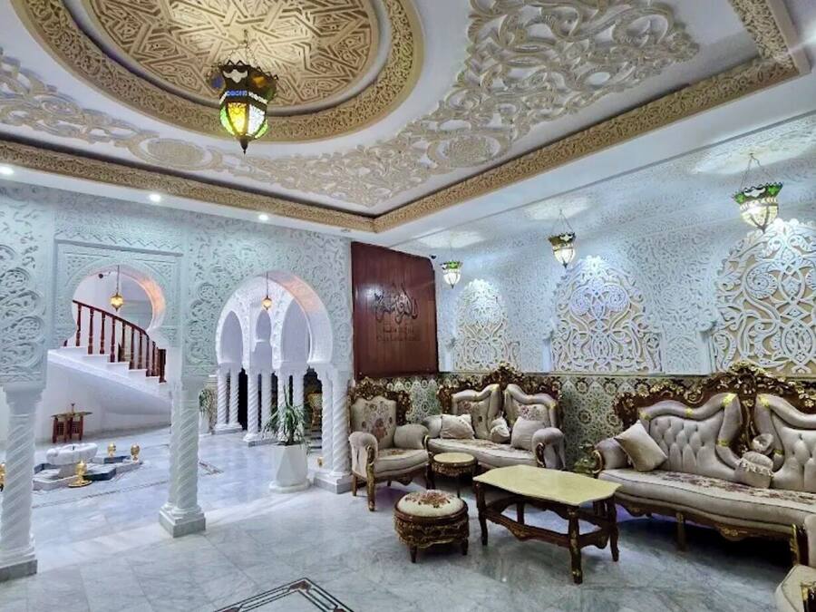 Um interior luxuoso com detalhes ornamentais no teto, uma escadaria imponente e áreas de estar requintadas.