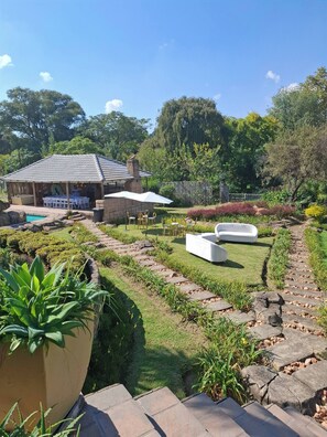 Um jardim com piscina, área de estar ao ar livre e um gazebo.