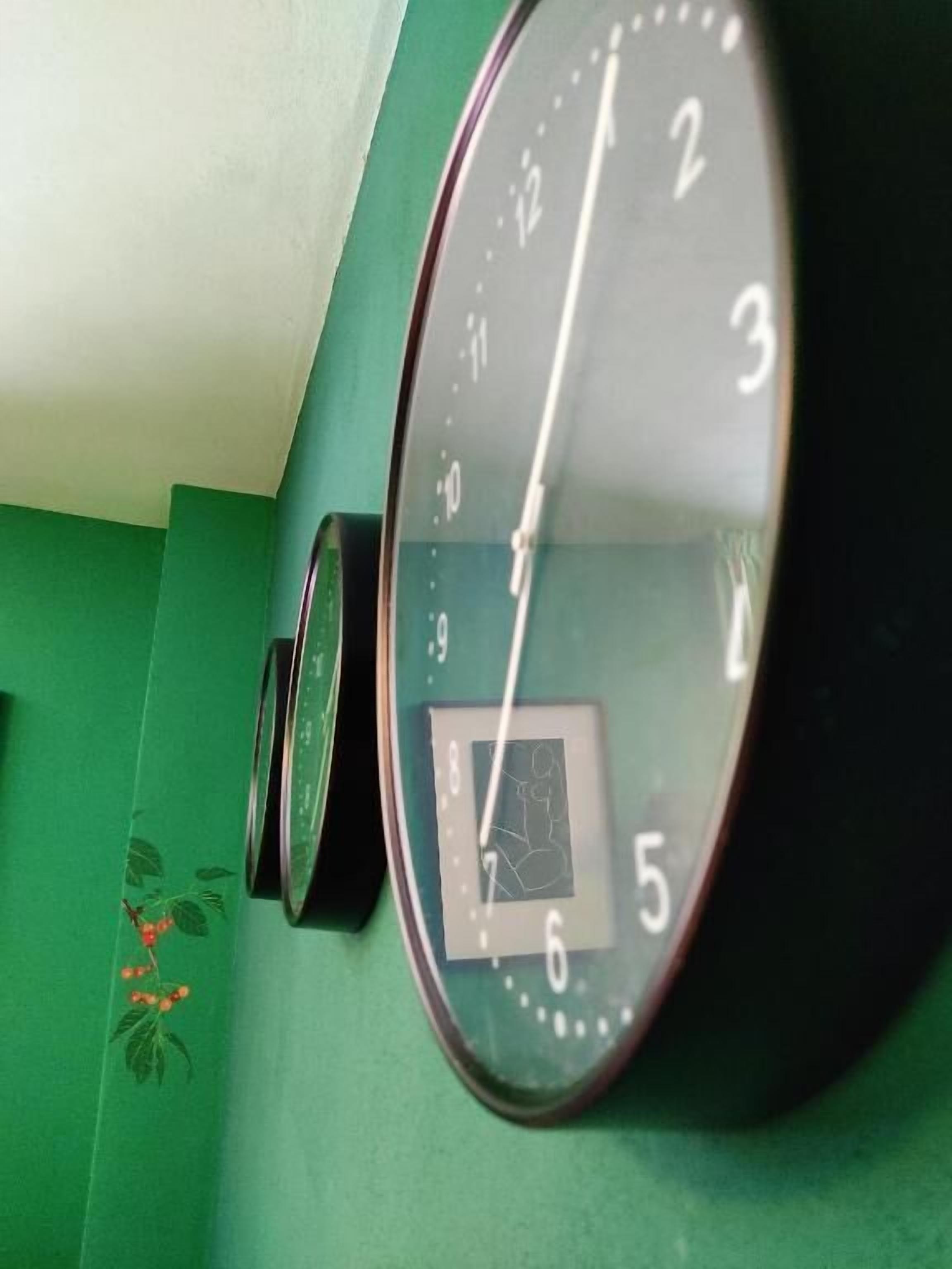 Relógio de parede com design minimalista, apresentando números e ponteiros para indicar as horas.