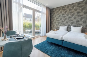 Quarto de hotel com cama, mesa para refeições com talheres e vista para o exterior.