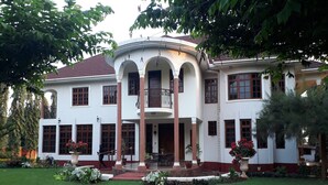 Uma casa de dois andares com uma varanda central, janelas amplas e um gramado bem cuidado.