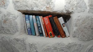 Uma coleção de livros dispostos numa reentrância de pedra.