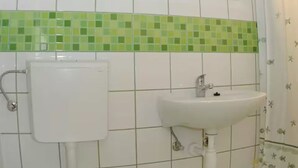 Uma casa de banho com uma pia branca, um toalete e um painel de azulejos verdes.