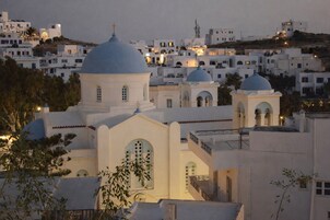 Um edifício branco com cúpula azul e janelas em arco, rodeado por outros edifícios brancos.