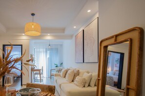 Uma sala de estar moderna com um sofá, uma mesa de jantar e um espelho grande.