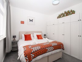 Quarto com cama, mesa de cabeceira, guarda-roupa e uma obra de arte na parede.