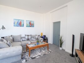 Sala de estar com sofá, mesa de centro e quadros nas paredes.