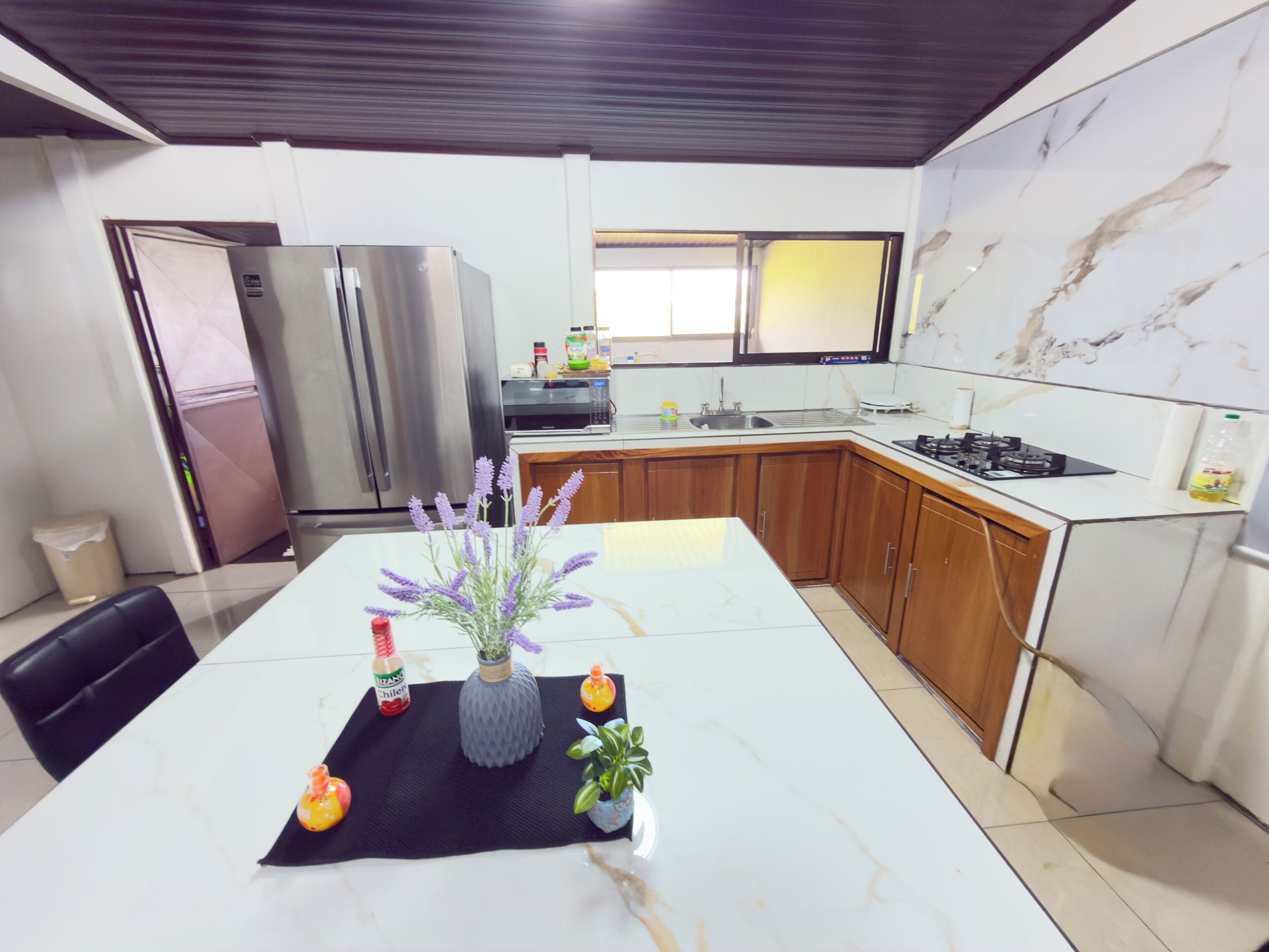 Uma cozinha moderna com ilha central, eletrodomésticos de aço inoxidável e armários de madeira.