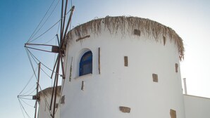 Um edifício branco com formato circular, uma pequena janela e um telhado de palha.
