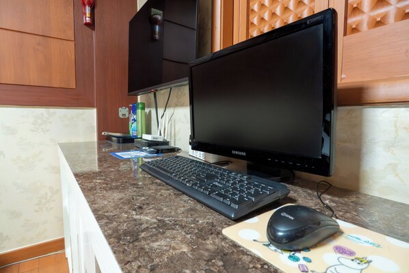 Uma bancada de cozinha com um computador, incluindo monitor, teclado e rato.