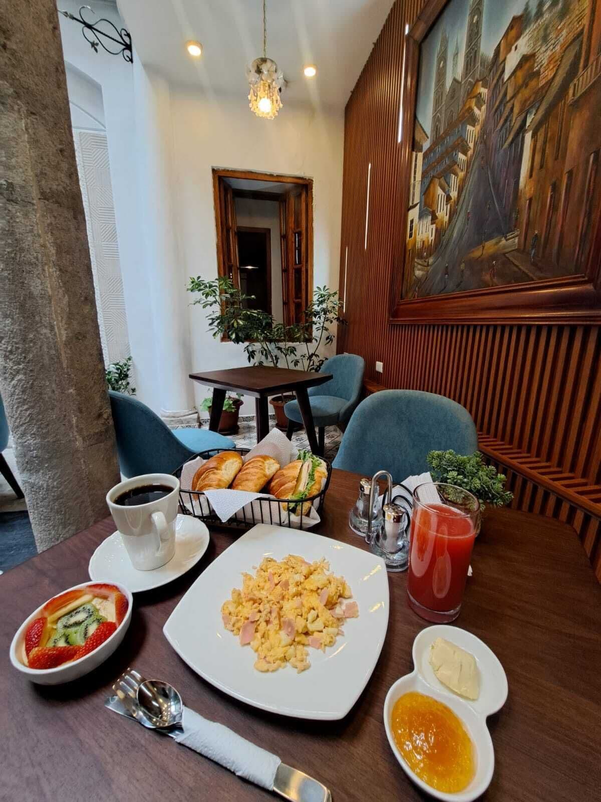 Mesa de jantar com itens de café da manhã, um quadro e vista para a rua.