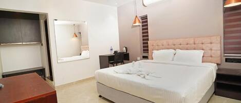 Quarto com cama, escrivaninha, cadeira, ventilador de teto e luminária pendente.
