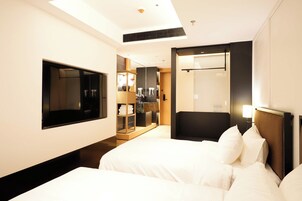 Quarto de hotel com duas camas, um espelho grande, um guarda-roupa e um closet espaçoso.