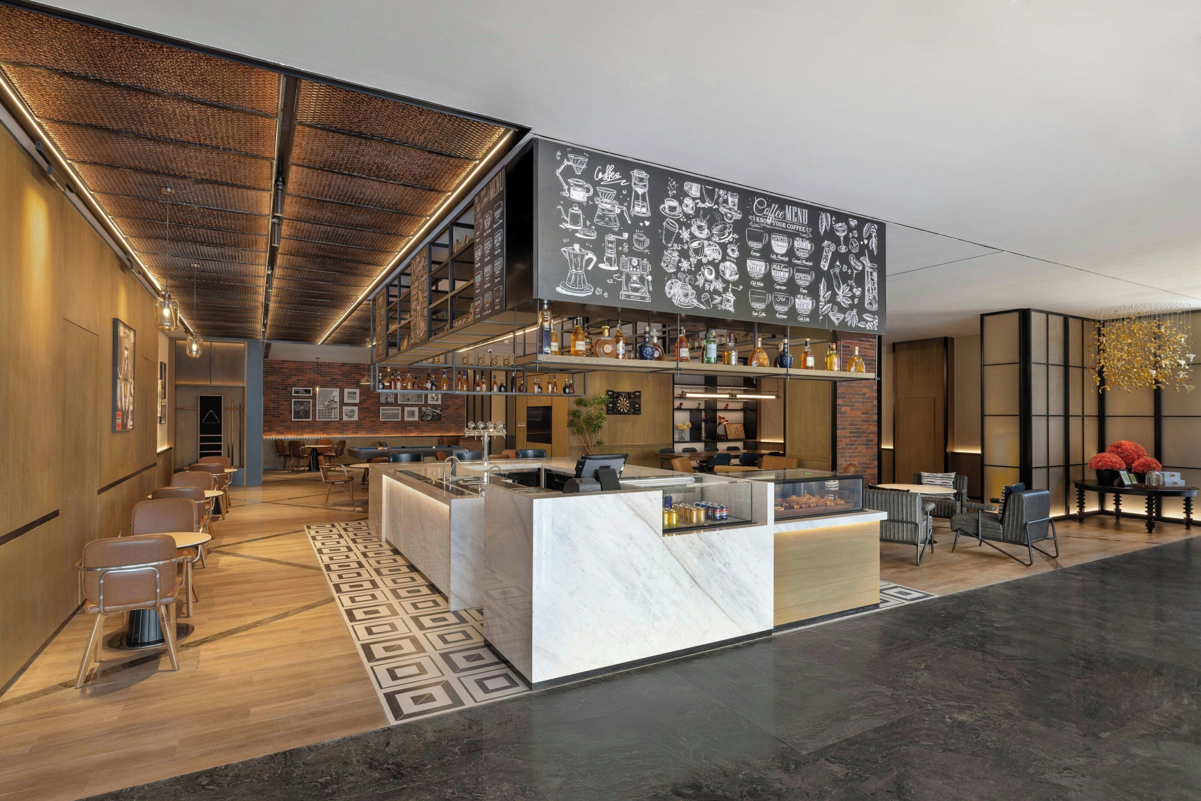 Uma área de bar moderna com balcão de mármore, assentos e uma parede decorativa com ilustrações sobre café.