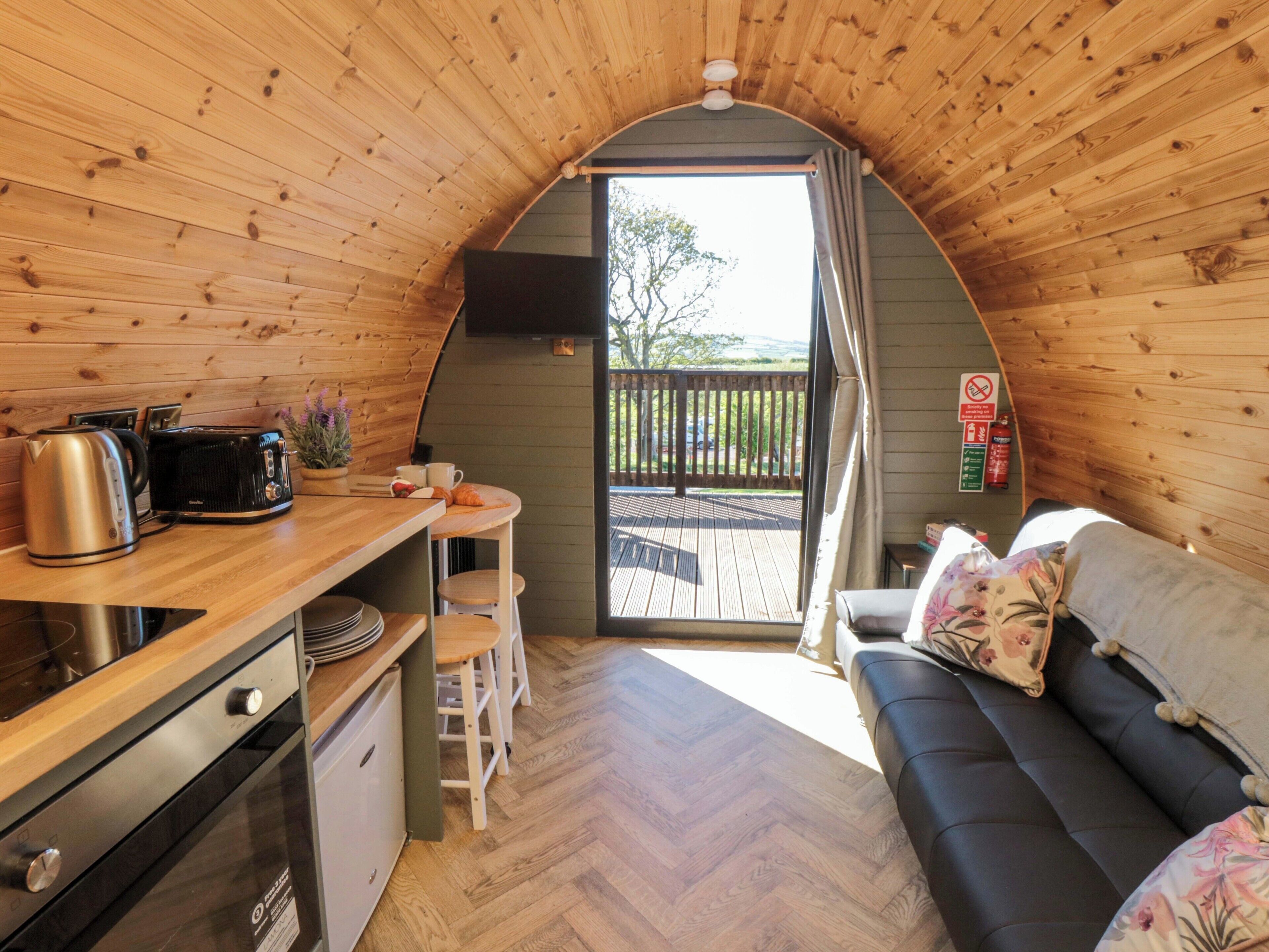 Um interior acolhedor em madeira, com cozinha compacta, espaço para refeições e um sofá.