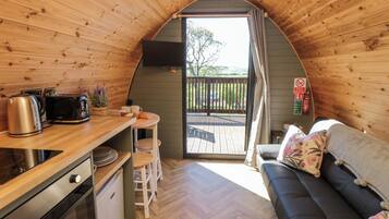 Um interior acolhedor em madeira, com cozinha compacta, espaço para refeições e um sofá.