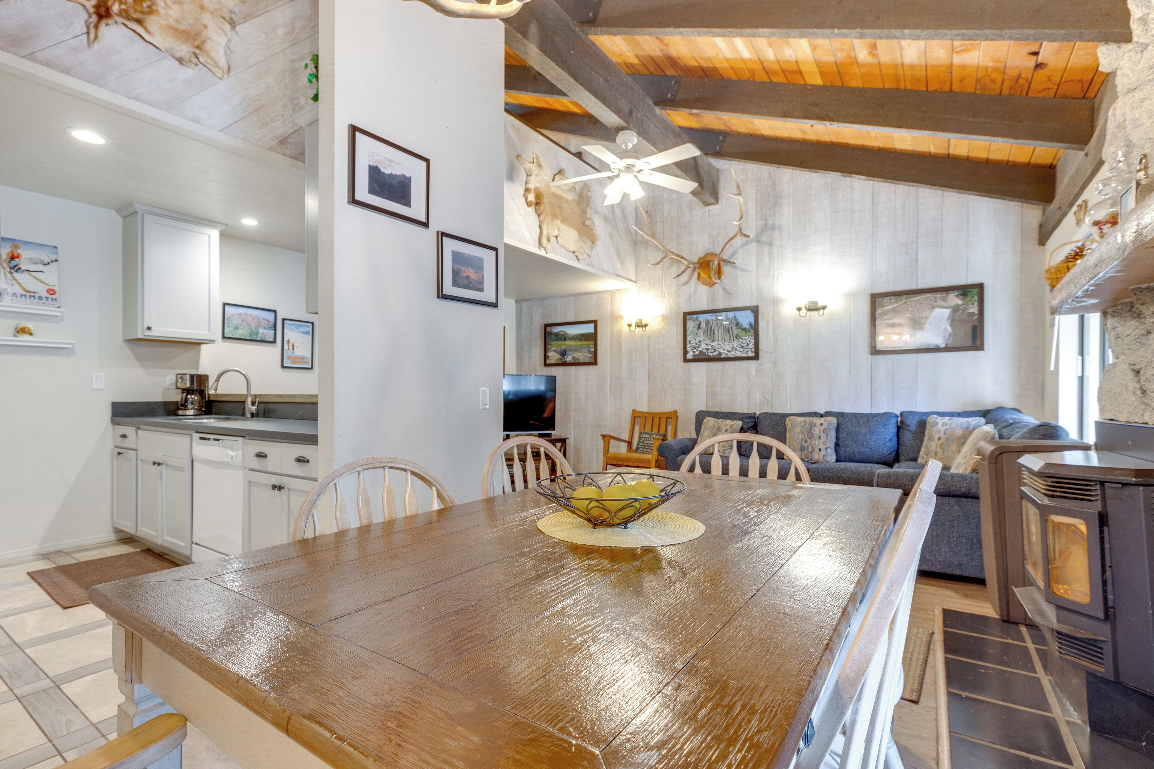 Uma cozinha ampla com mesa de madeira, armários brancos e lareira de pedra.