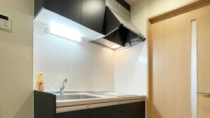 Cozinha moderna com armários pretos, pia de aço inoxidável e porta de madeira.