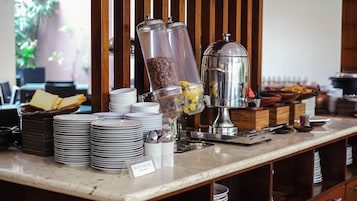 Disposição de buffet com dispensadores de café, pratos e tigelas.