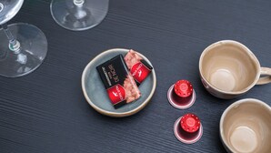 Uma mesa de madeira escura com um prato de chocolate, duas taças de vinho e duas canecas de cerâmica.