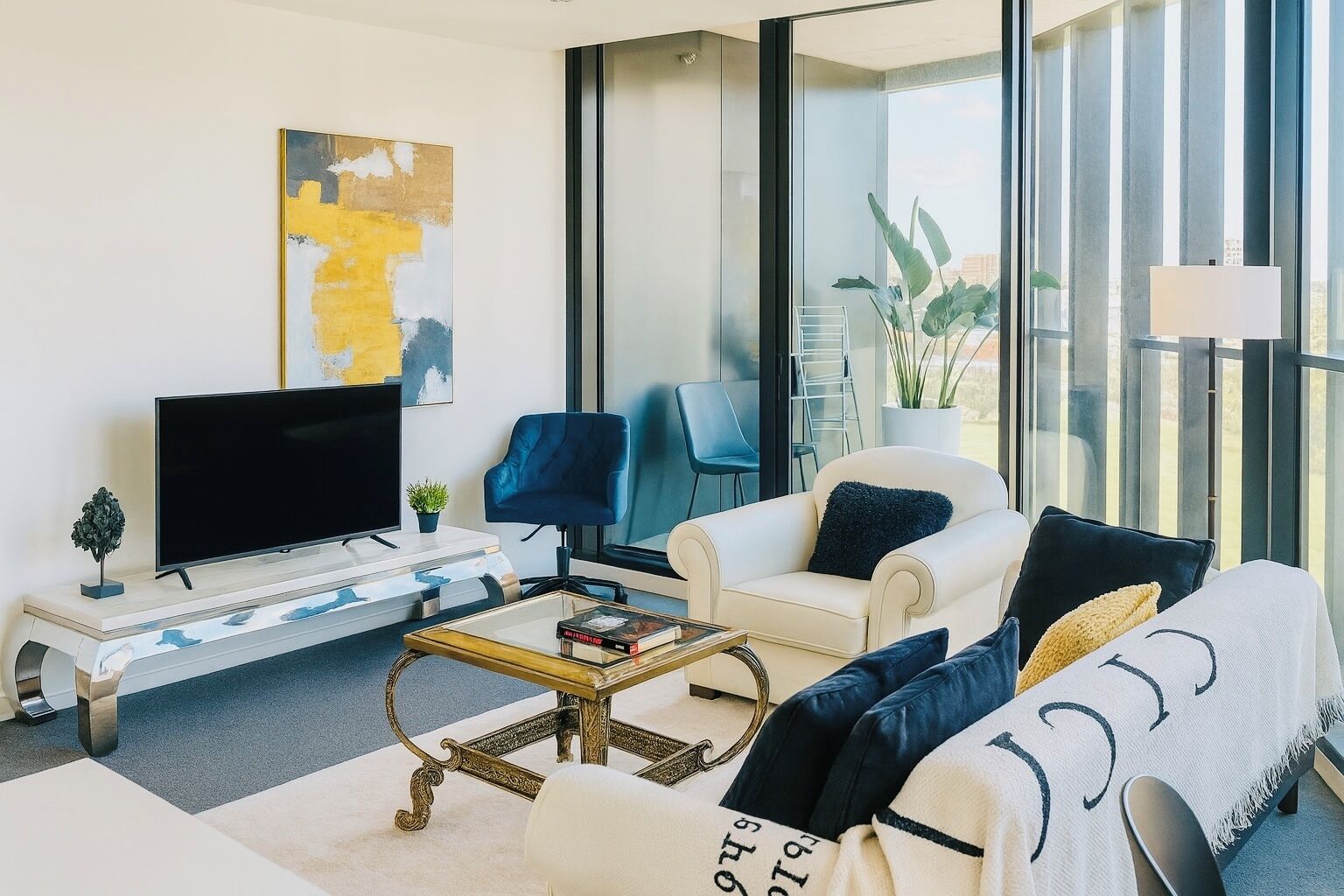 Uma sala de estar moderna com uma TV de tela plana, uma mesa de centro, um sofá e uma poltrona.