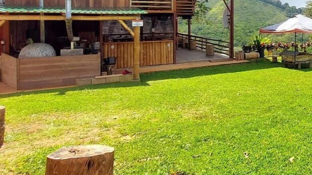 Uma cabana de madeira com varanda, espaço para churrasco e vista para as colinas ao redor.
