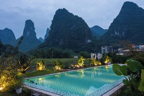 Piscina com vista para montanhas e um edifício ao fundo.