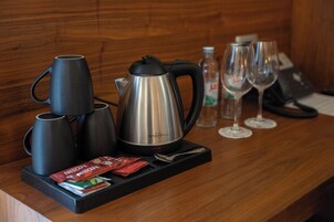 Uma estação de café com chaleira, xícaras e uma bandeja com sachês de café.
