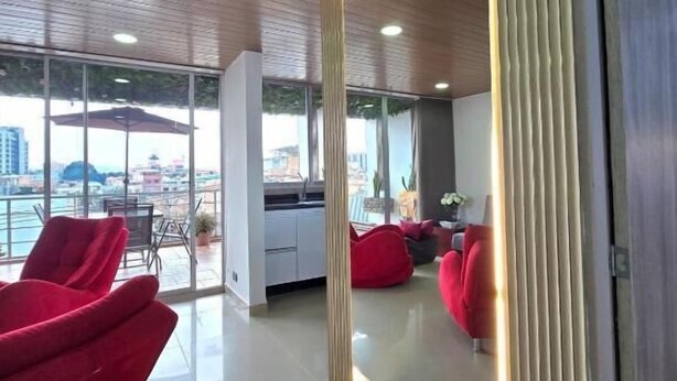 Um interior moderno com cozinha, cadeiras vermelhas e uma grande janela com vista para a cidade.