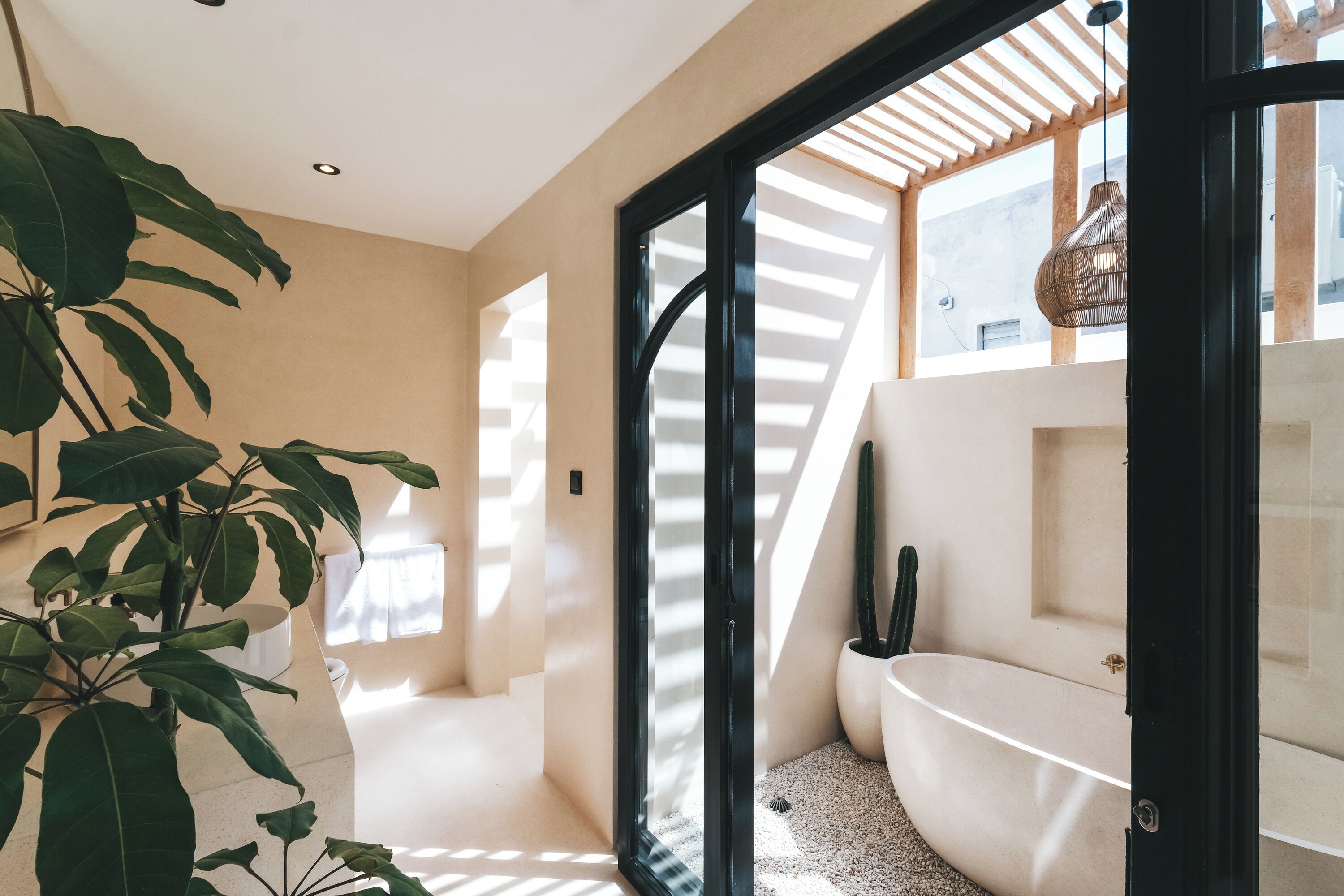 Um interior moderno com uma planta grande, uma banheira branca e estrutura de teto em madeira.