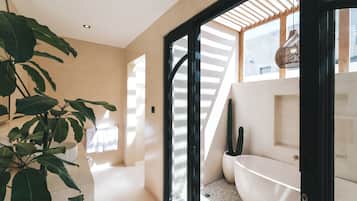 Um interior moderno com uma planta grande, uma banheira branca e estrutura de teto em madeira.