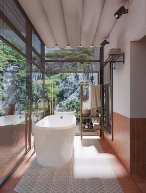 Uma casa de banho moderna com uma banheira independente, chuveiro e uma grande janela com vista para uma paisagem montanhosa.