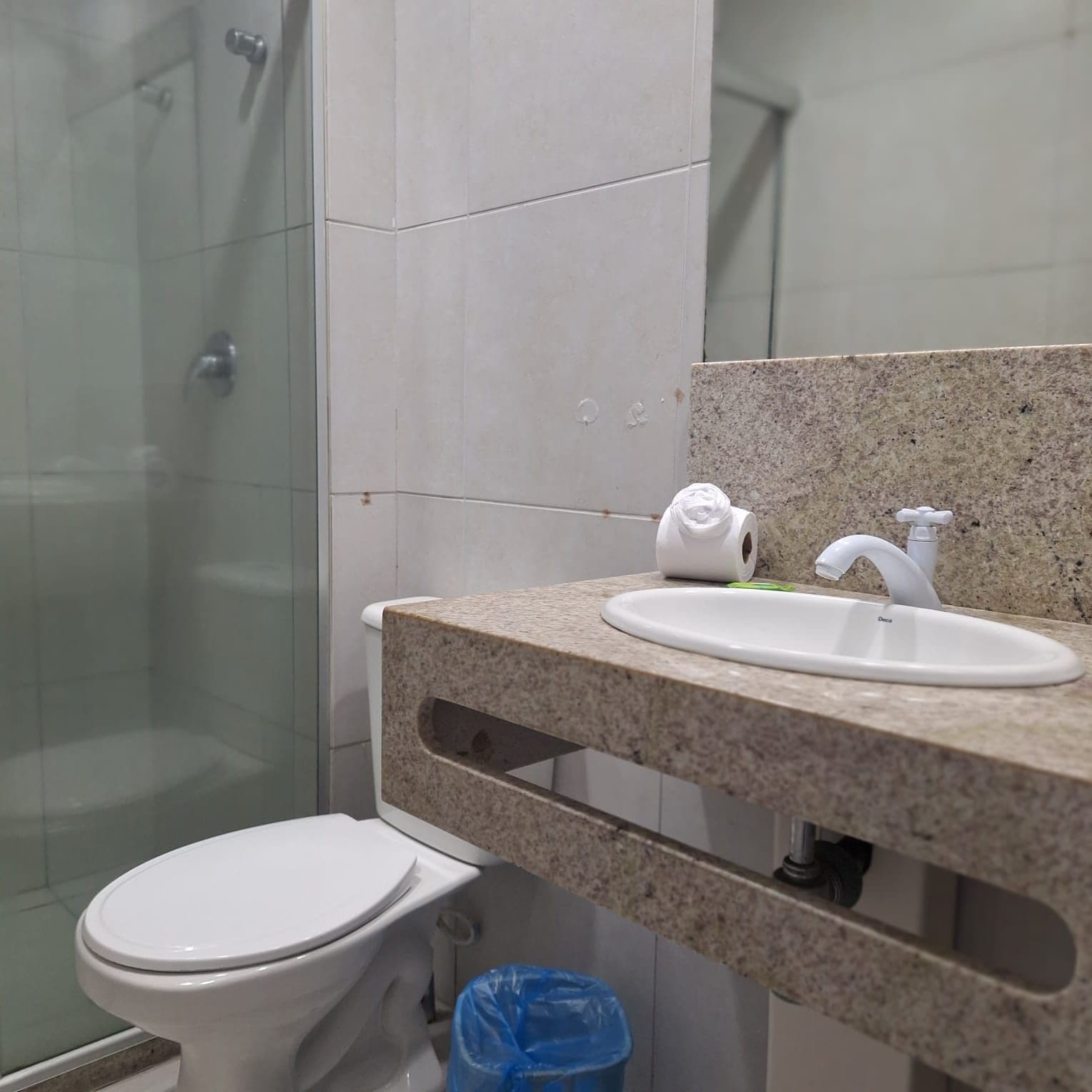 Casa de banho com sanita, lavatório e chuveiro.