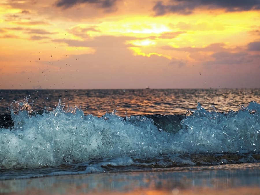 Um pôr do sol sobre o oceano, com ondas quebrando na costa.
