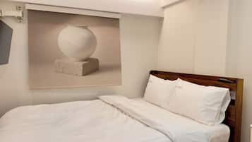 Cama bem arrumada com lençóis brancos, cabeceira de madeira e controle remoto do lado direito.