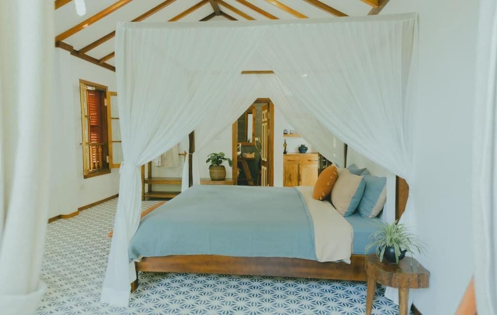 Quarto com cama de dossel, soalho estampado e estrutura de teto em madeira.