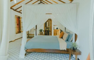 Quarto com cama de dossel, soalho estampado e estrutura de teto em madeira.