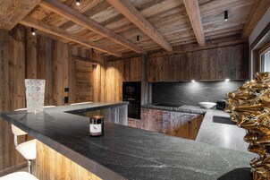 Cozinha moderna com paredes de madeira, bancada preta e uma escultura dourada singular.