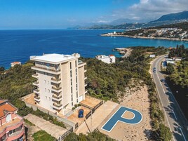 Um edifício com vários andares e uma área de estacionamento identificada com a letra 'P'.