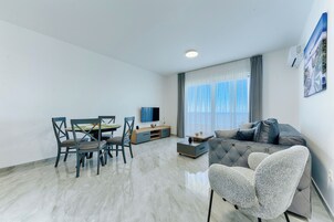 Uma sala de estar moderna com área de jantar, um sofá e uma televisão.