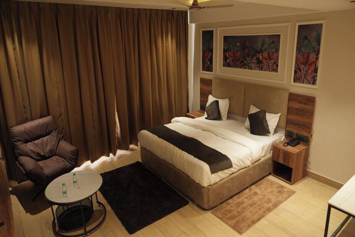 Quarto com cama, cadeira, mesinha, mesa de cabeceira e obras de arte na parede.