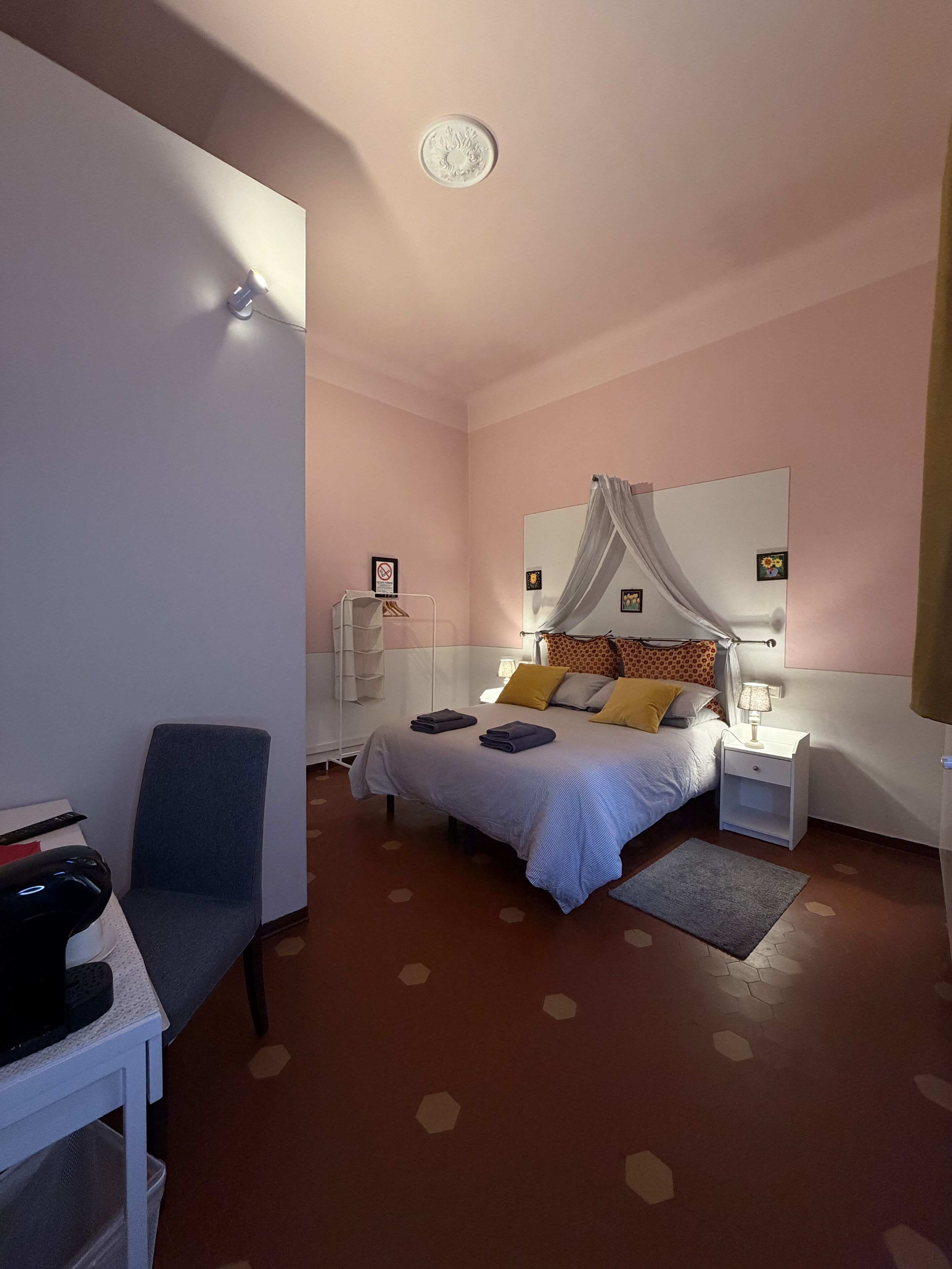 Um quarto com uma cama, mesas de cabeceira, uma cadeira e uma escrivaninha.