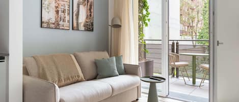 Sala de estar com sofá, mesinha e varanda com móveis para área externa.