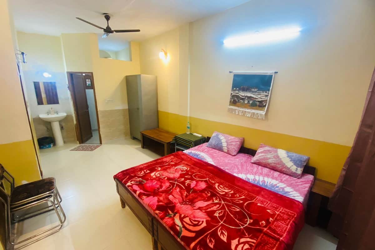 Quarto com cama, mesas de cabeceira, espelho, guarda-roupa e banheiro com pia.