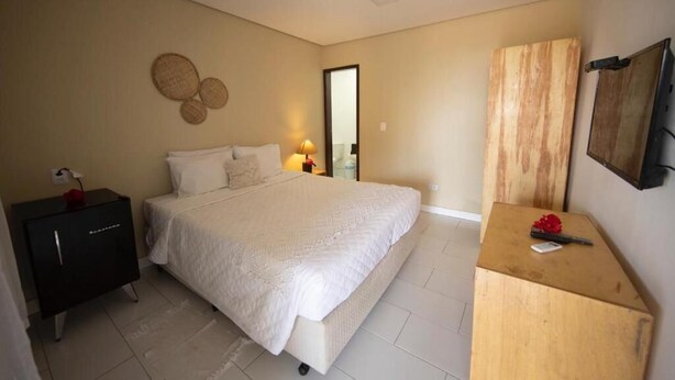 Quarto com cama, mesa de cabeceira, cômoda e espelho.