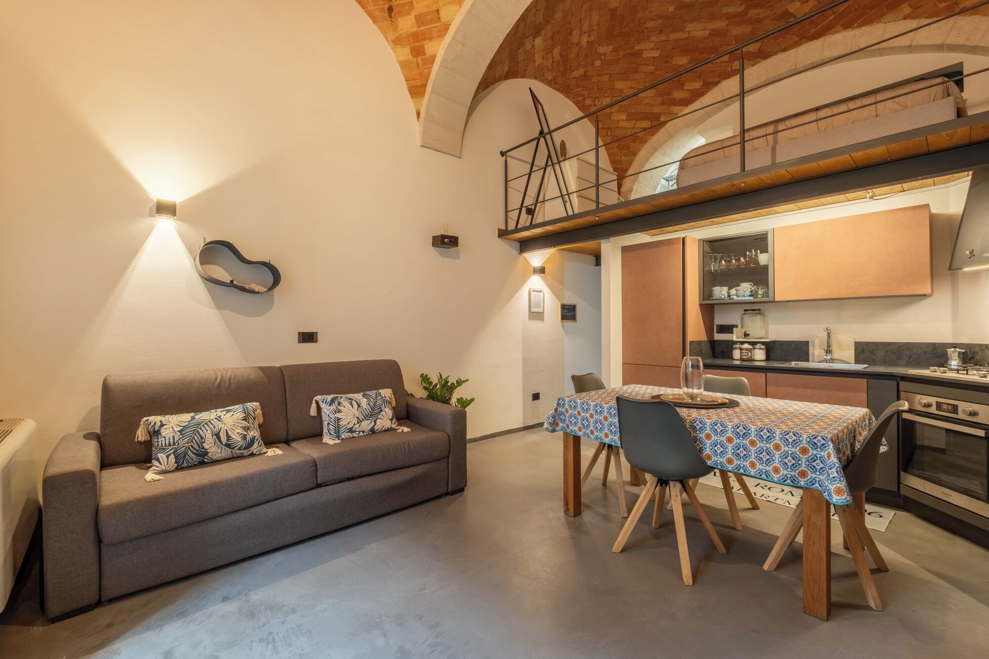 Um espaço de estar moderno com sofá, mesa de jantar e cozinha.