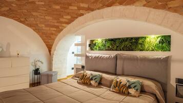 Quarto com teto de tijolos, cama com colcha bege e planta verde fixada na parede.