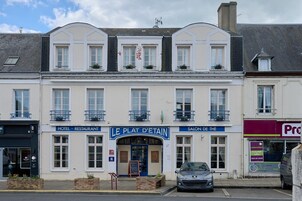 Um hotel com restaurante, salão de festas e um carro estacionado em frente.