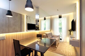 Uma sala de jantar moderna com uma mesa e cadeiras de madeira, uma televisão de tela plana na parede e um sofá ao fundo.