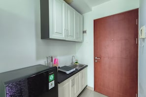 Uma cozinha com geladeira, pia, armários e uma porta.